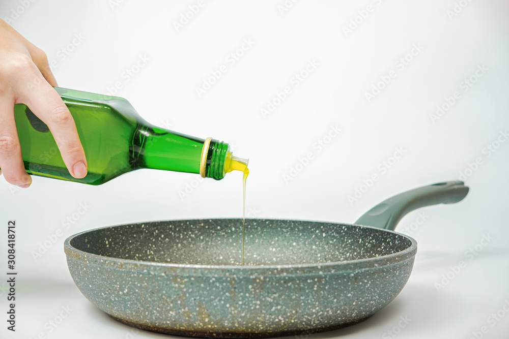 Pouring oil onto a frying pan. Cooking with vegetable oil, concept of ...