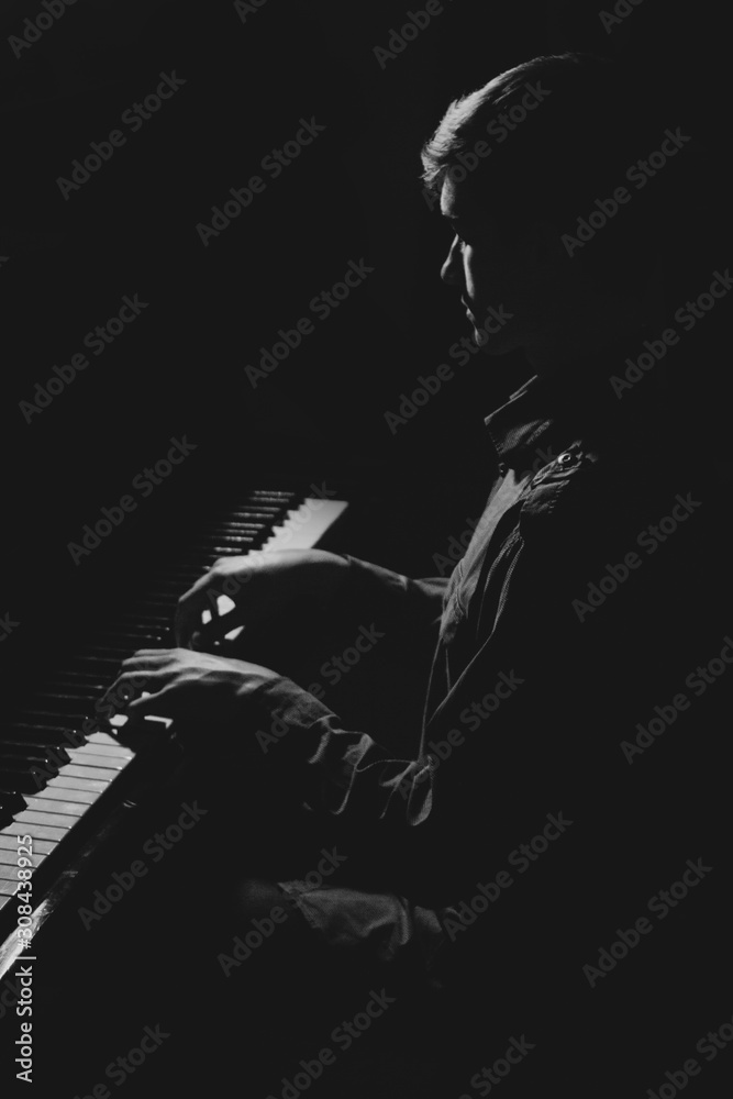 young man sitting at the piano. boy emotionally plays the keyboard ...