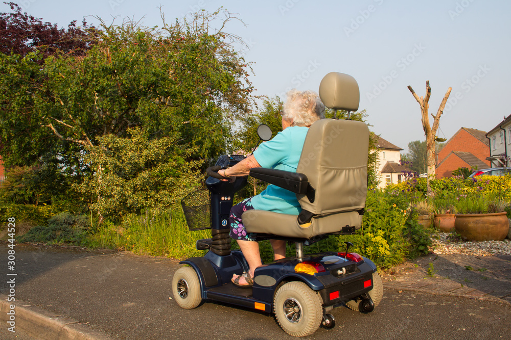 Foto de Elderly lady using her mobility scooter to get around outdoors ...