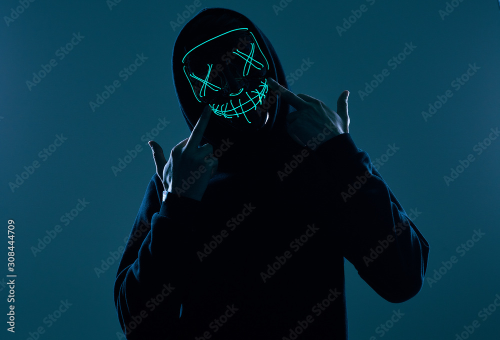 Anonymous man in black hoodie hiding his face behind a neon mask Stock ...