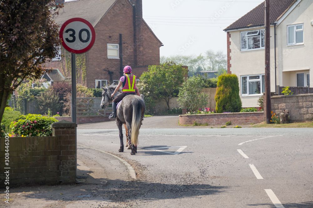 Stockfoto Riding road safety-young woman rides her horse through a ...