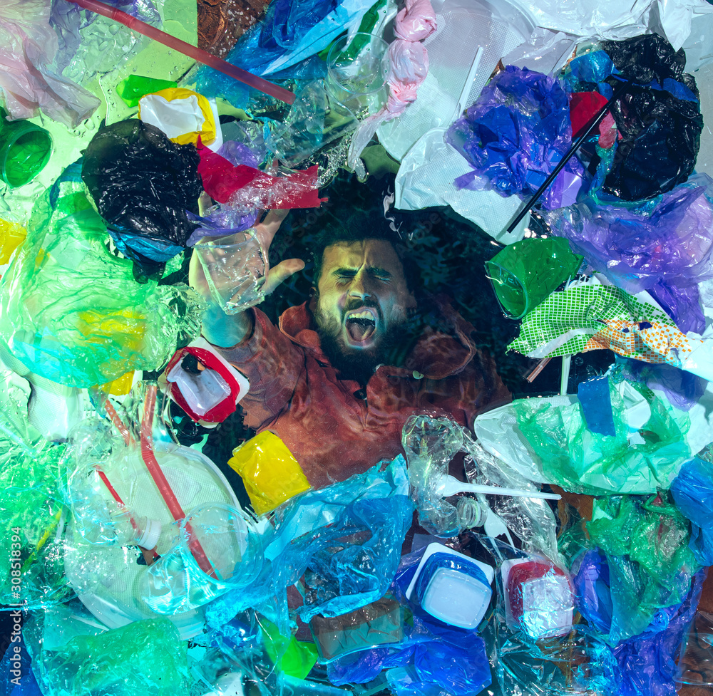 Man drowning in water under plastic recipients pile, garbage. Used ...