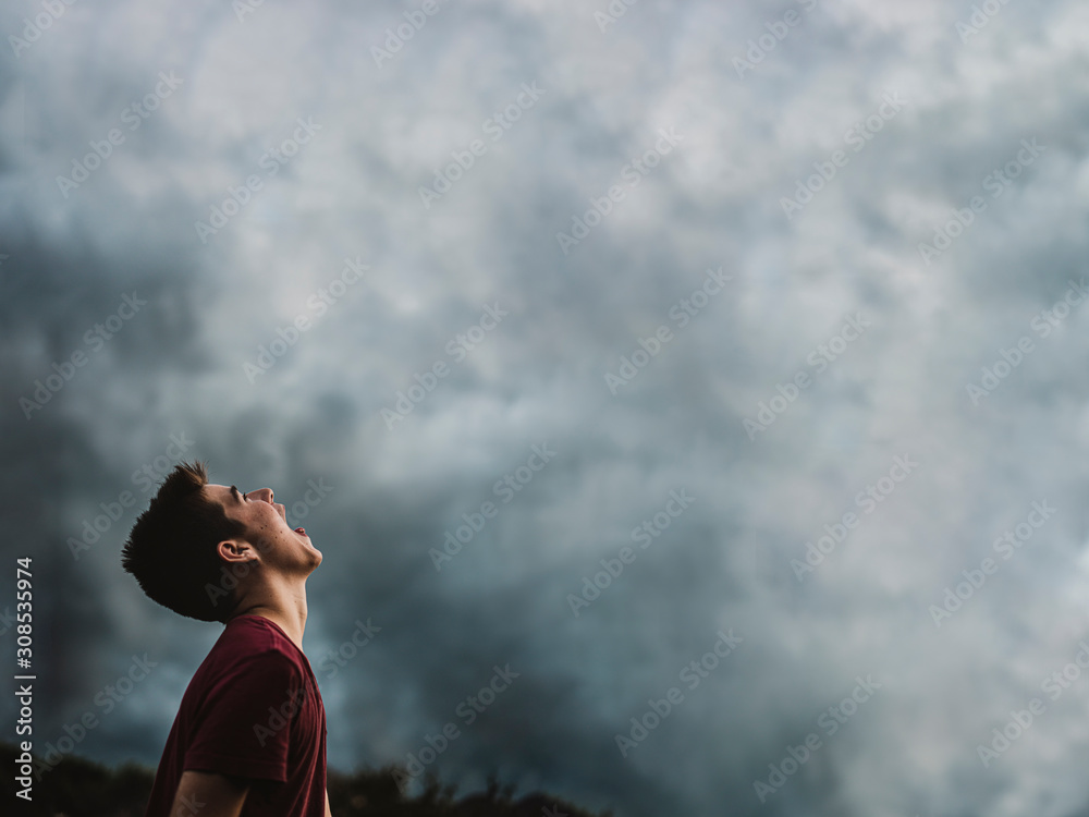 Teen boy looking up at dark cloudy sky with his mouth open wide. Stock ...