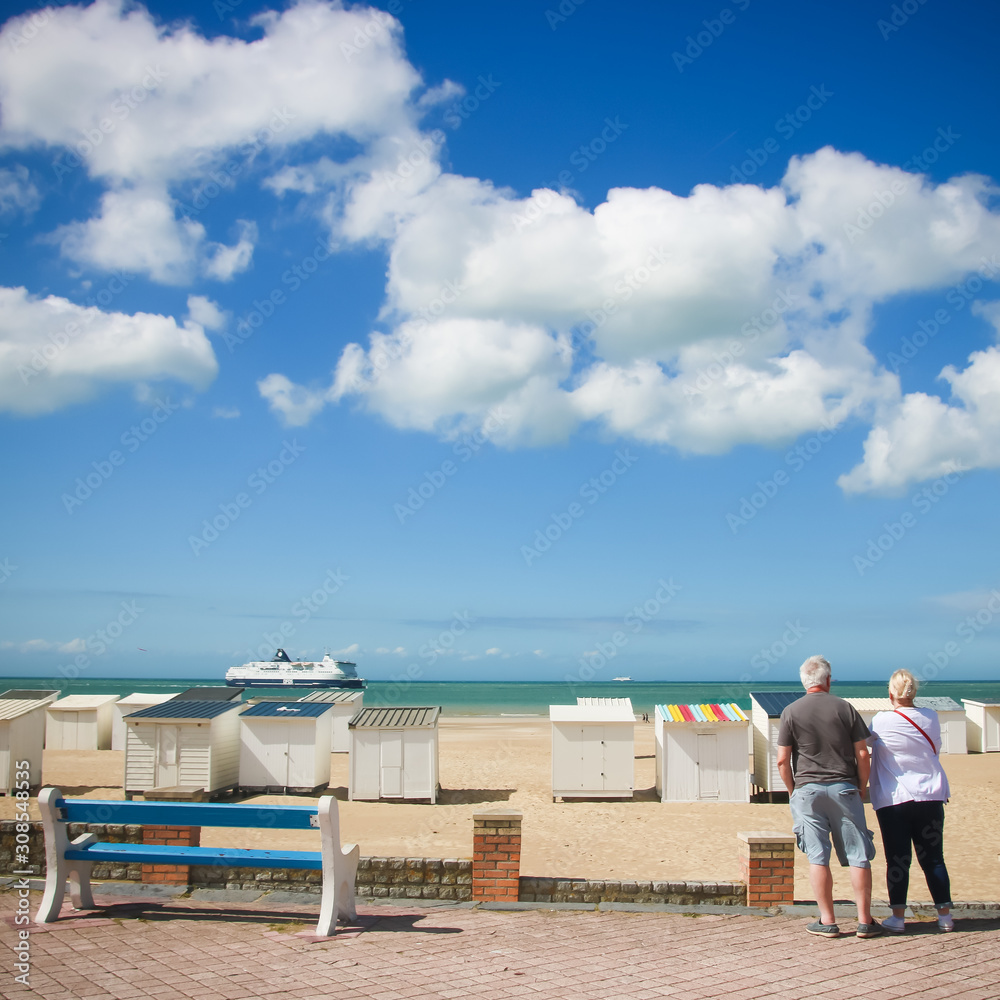 couple au bord de la Manche à Calais devant la plage et un ferry qui ...