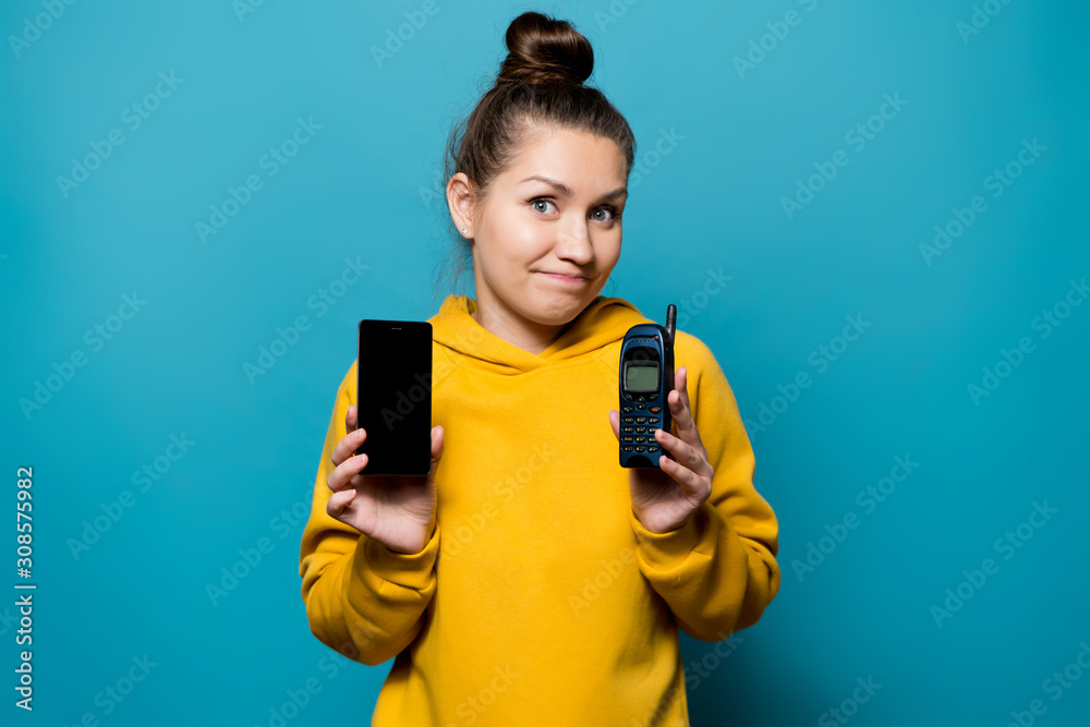 girl shows an old phone with buttons and a smartphone, restrained ...