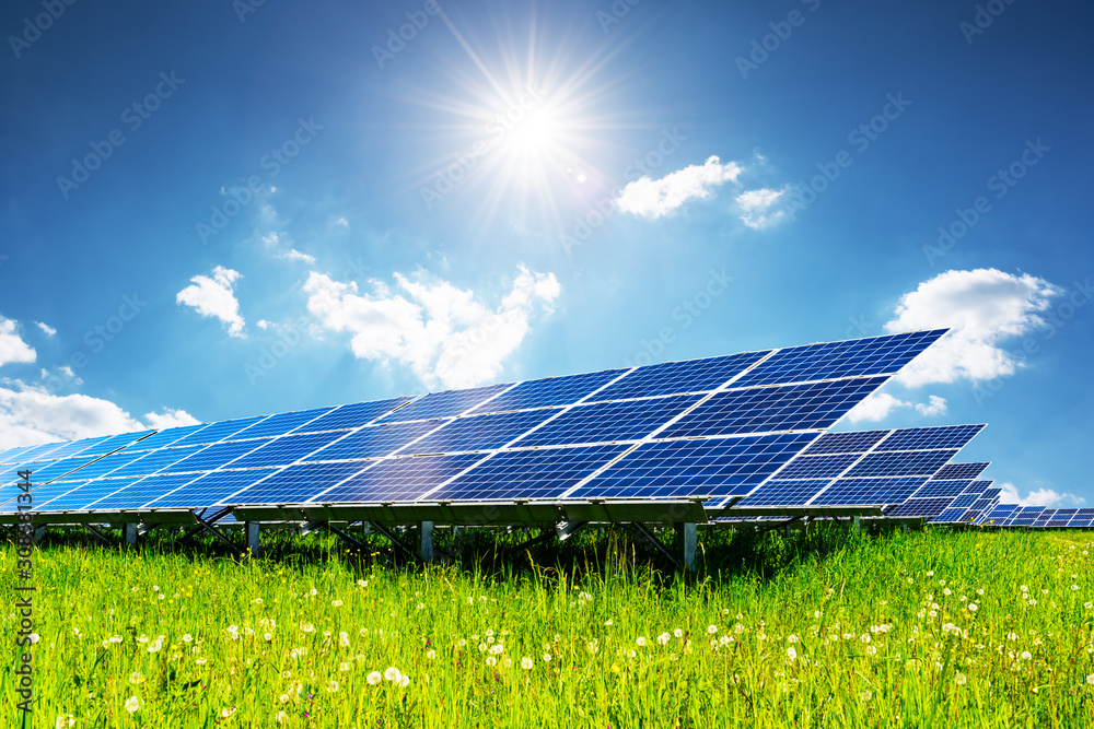 Solar panel under blue sky with sun. Green grass and cloudy sky ...
