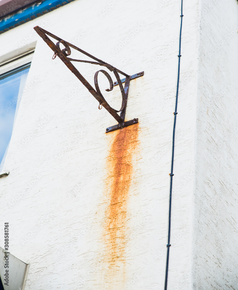 Rusty old metal wall plant basket hanger on white wall with an orange ...