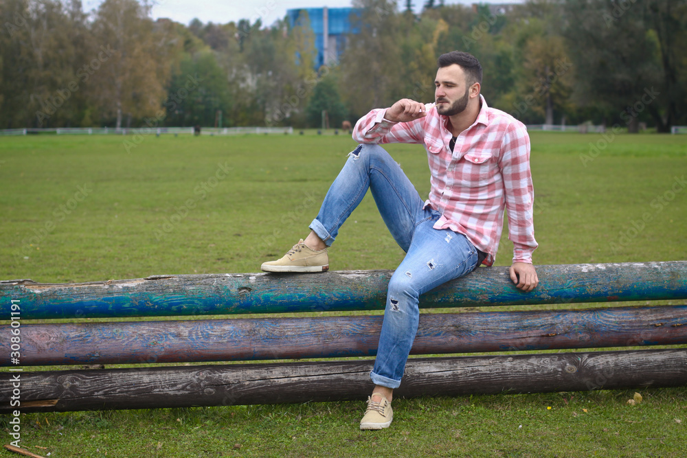 Young handsome guy Cowboy. male farmer is sitting on his fence on his ...