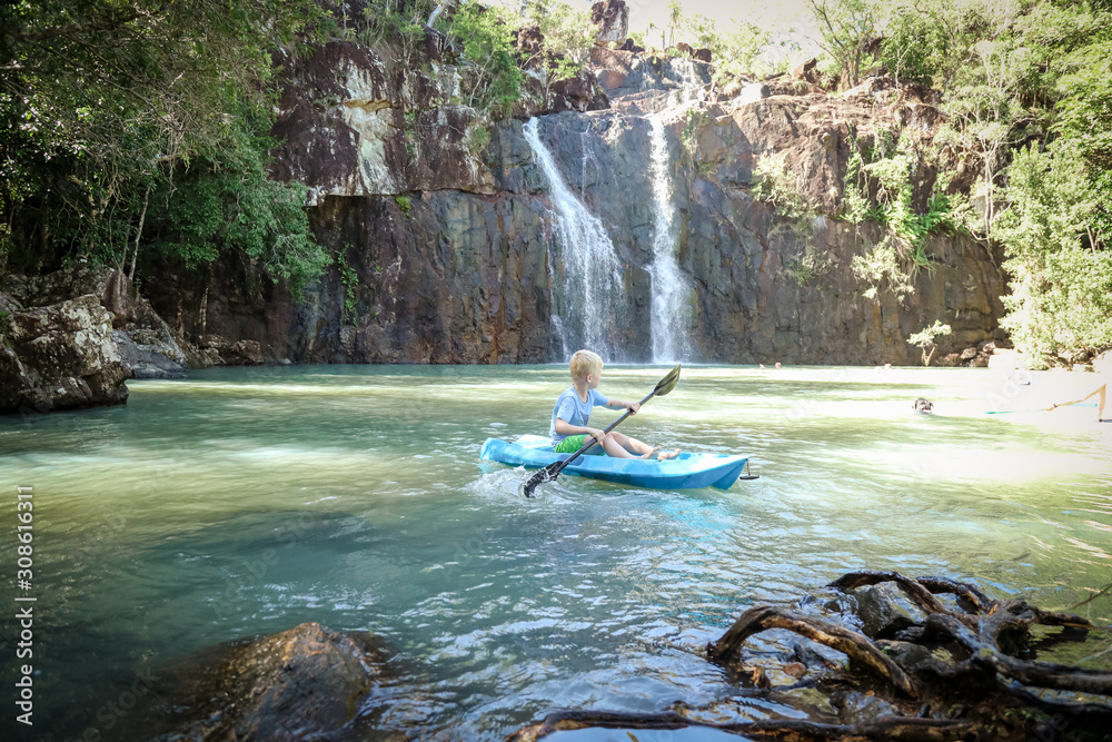 Foto de Young boy kayaking with paddle in cool blue water at Cedar ...