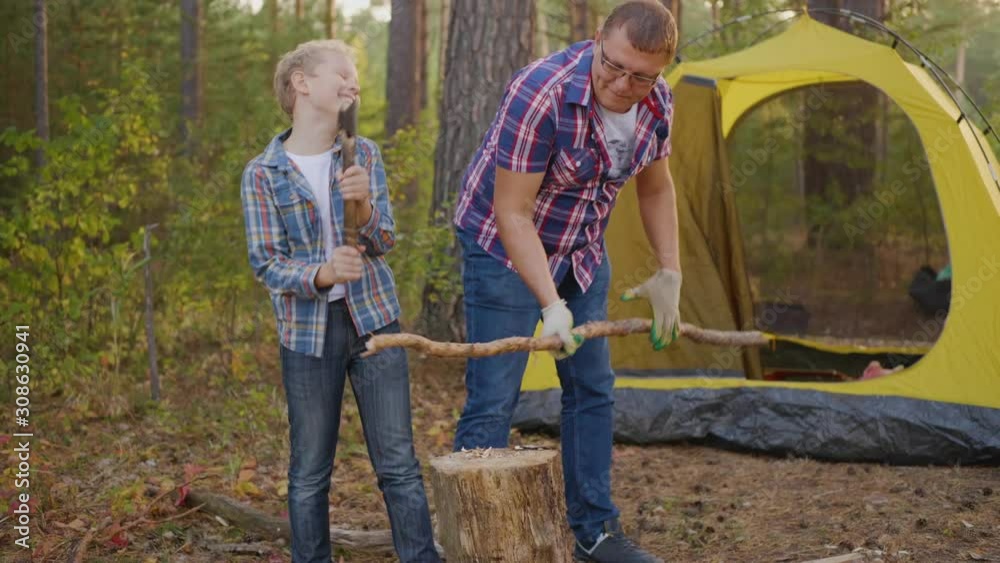 Father and son chopping wood in camping. Middle aged father holding log ...