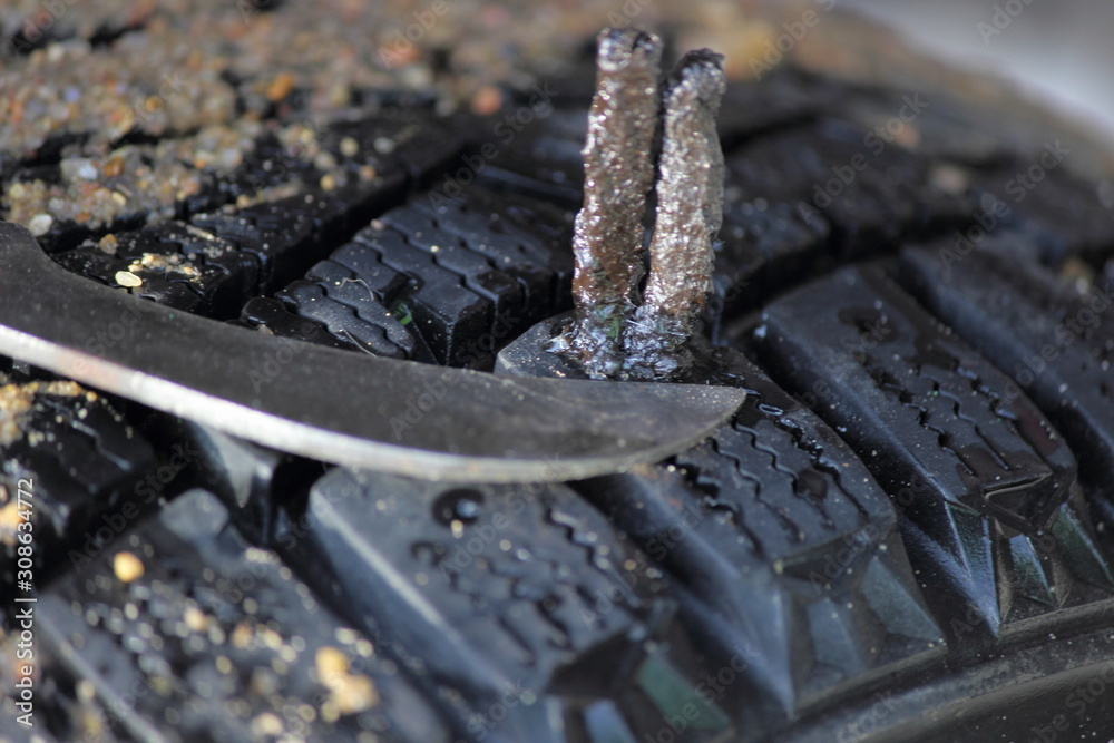 A knife cuts off remains repair compound from a car tire, punctured ...