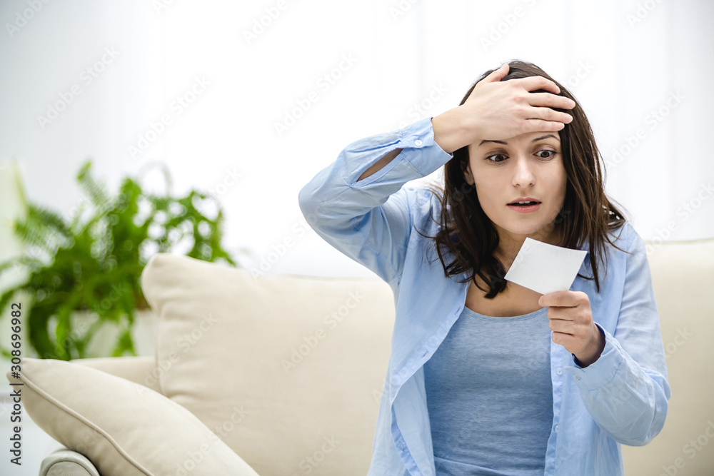 Confused and shocked woman is holding lottery ticket and looking at it ...