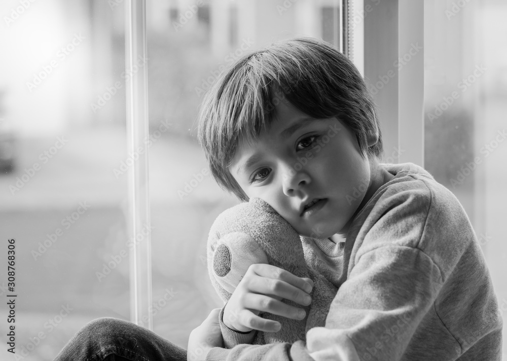 Emotional portrait of upset little boy sitting next to window, Kid sad face, Unhappy child ...