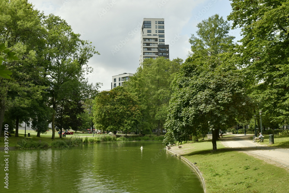 Le parc Léopold avec son étang et la tour d'appartement de haut ...