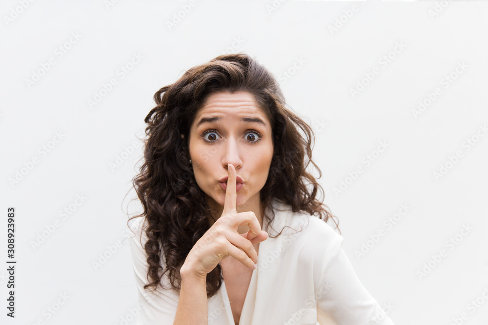 Excited woman with wide eyes making shh gesture. Wavy haired young ...