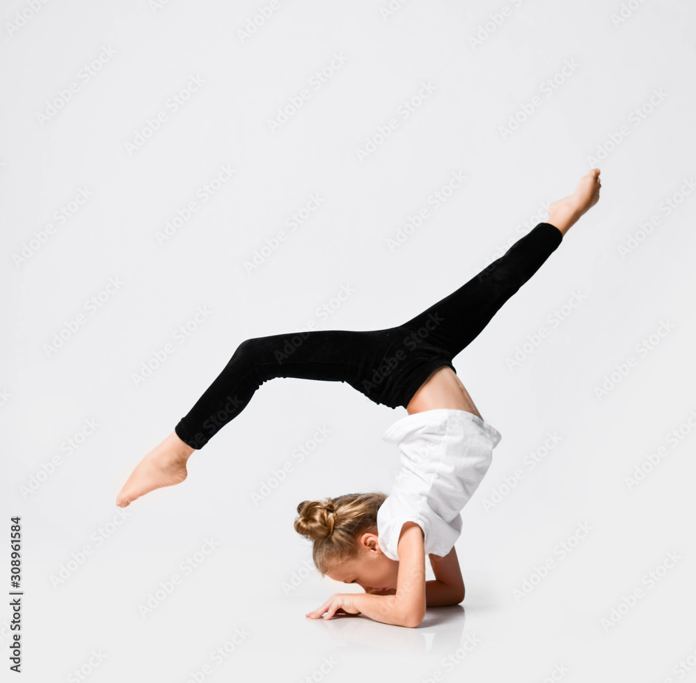 Slim athletic kid girl is doing gymnastic acrobatics exercises ...