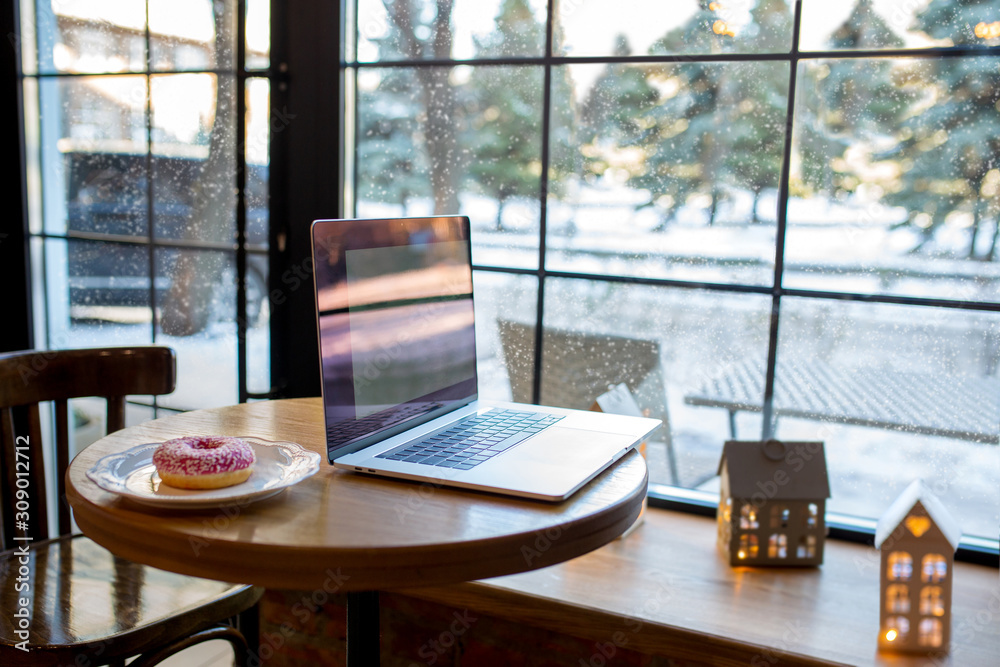 Workplace with a laptop. A table with a large window, coffee and a ...