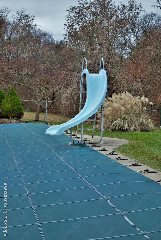 backyard swimming pool with diving board and pool slide tarped up and ...