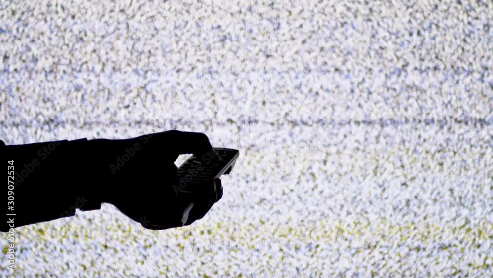 Silhouette of a Hand Holding a TV Remote on TV Screen Background with ...