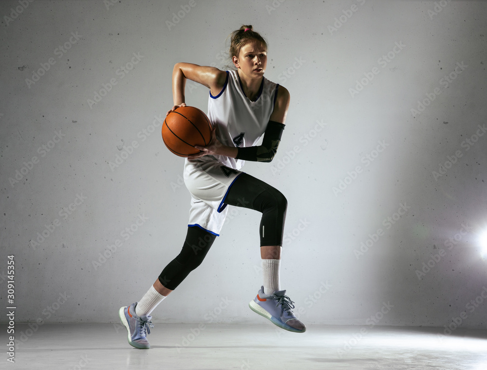 Young caucasian female basketball player of team in action, motion in ...