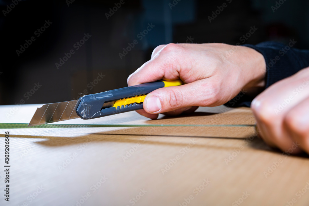 Man using an utility knife to open a cardboard box. Male hand holding a ...