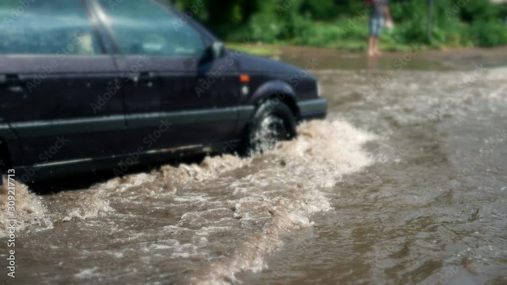 Car traffic on the flooded city street after heavy rain. Disaster flood ...