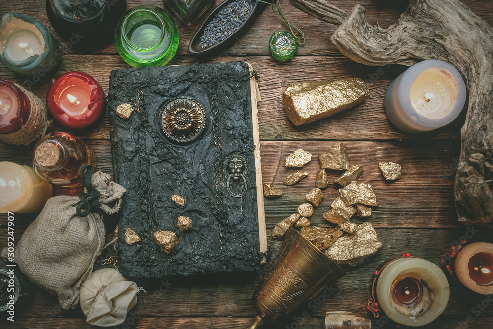 Golden stones and ancient magic book on alchemist table concept ...