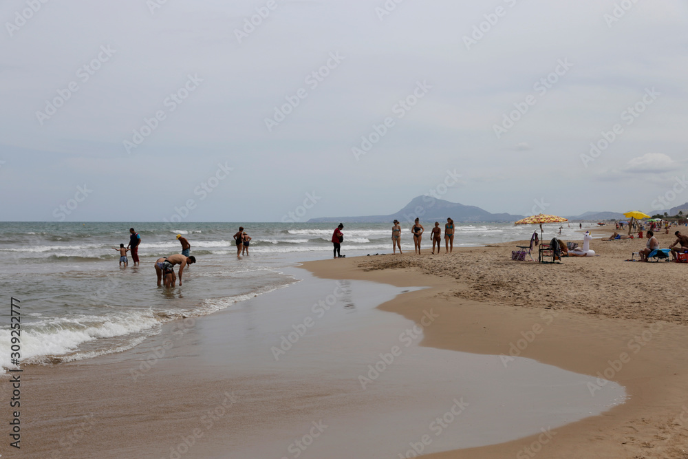 People collecting seashells on the beach. Beautiful sand beach in Spain ...