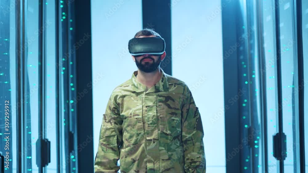 Bearded army soldier is wearing modern VR headset, standing in high ...