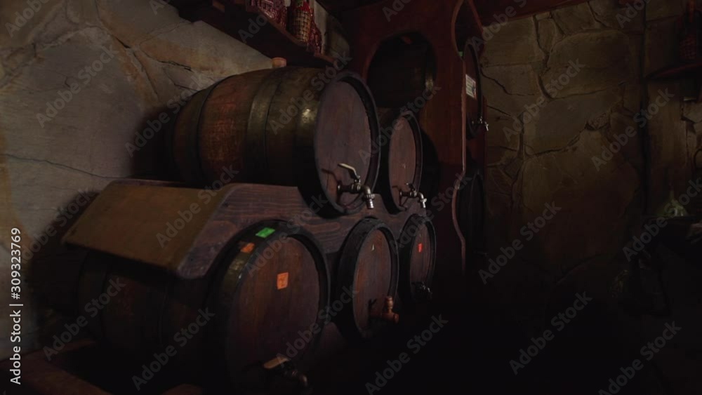 Wooden barrels with old wine are stored in dark basement in house ...