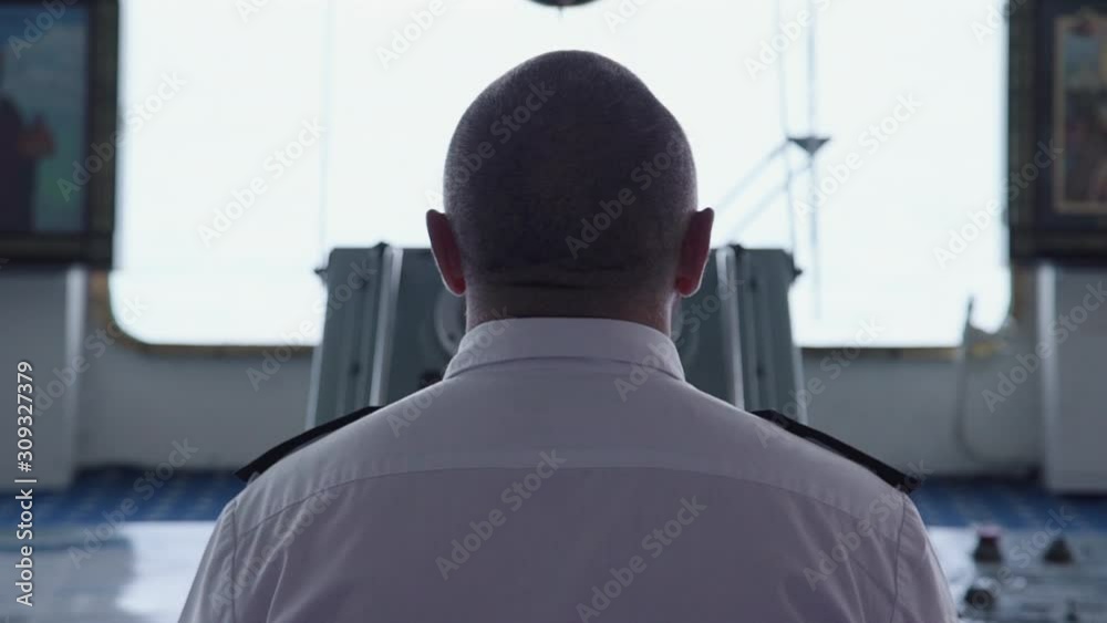 back view of captain controlling and driving ship. driver at dashboard ...