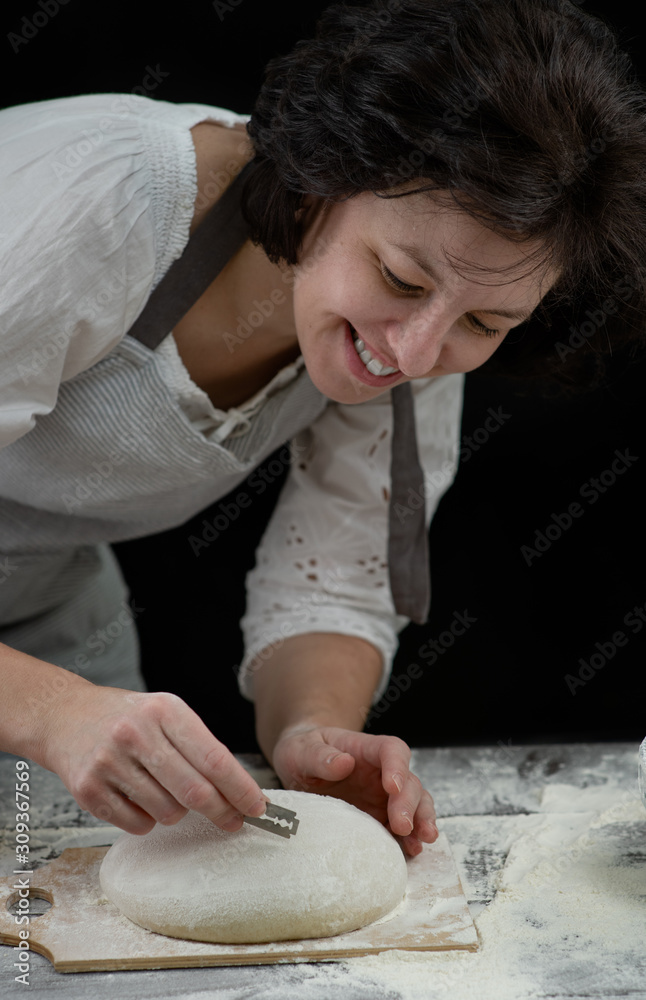 Female Baker making patterns on raw bread using a knife ot blade to ...