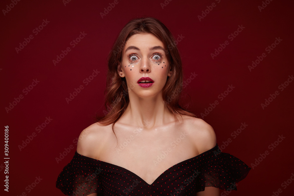 Open-eyed young pretty female with brown wavy hair wearing festive ...