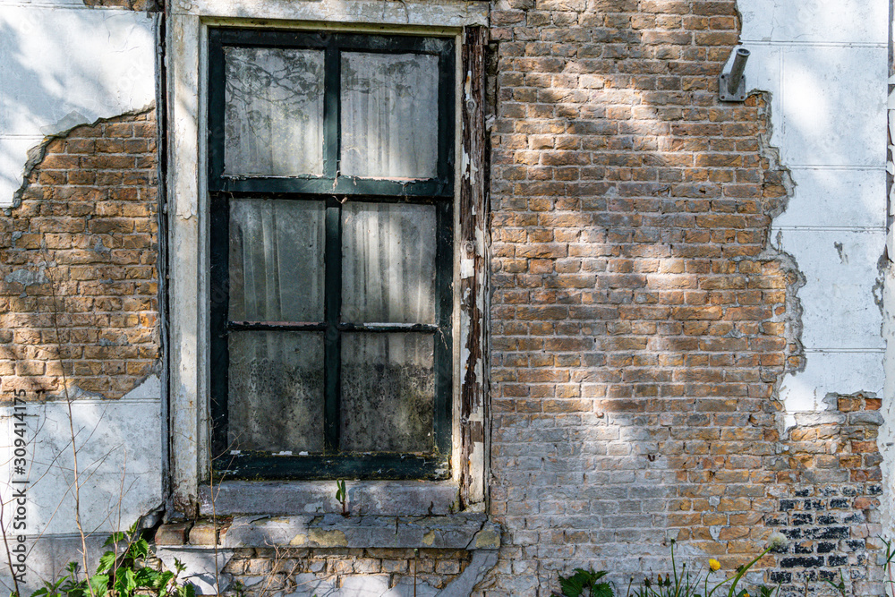 Slanted window with smudgy curtains behind it in a derelict house ...