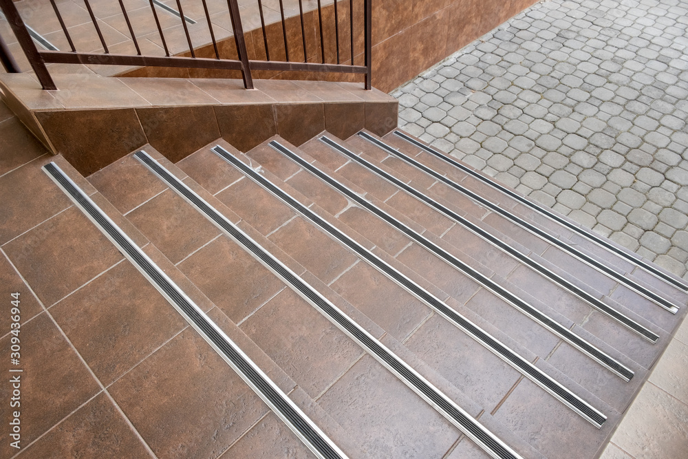 Concrete entrance stairs covered with ceramic tiles with metal railings ...