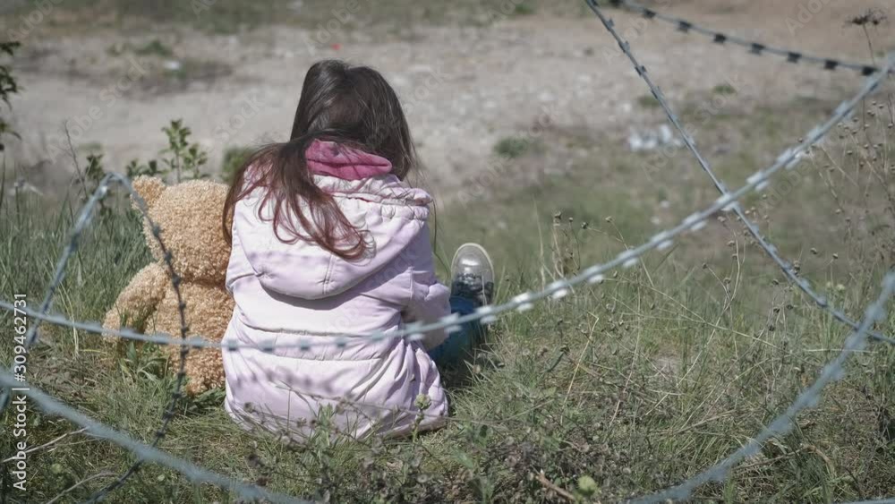 Childhood behind the barbed wire. Homeless lonely child. Little girl ...