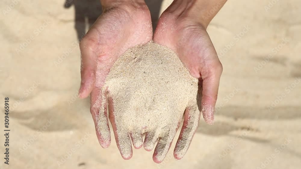 Woman scoop sand on the beach in daytime with two hands up, wind blow ...