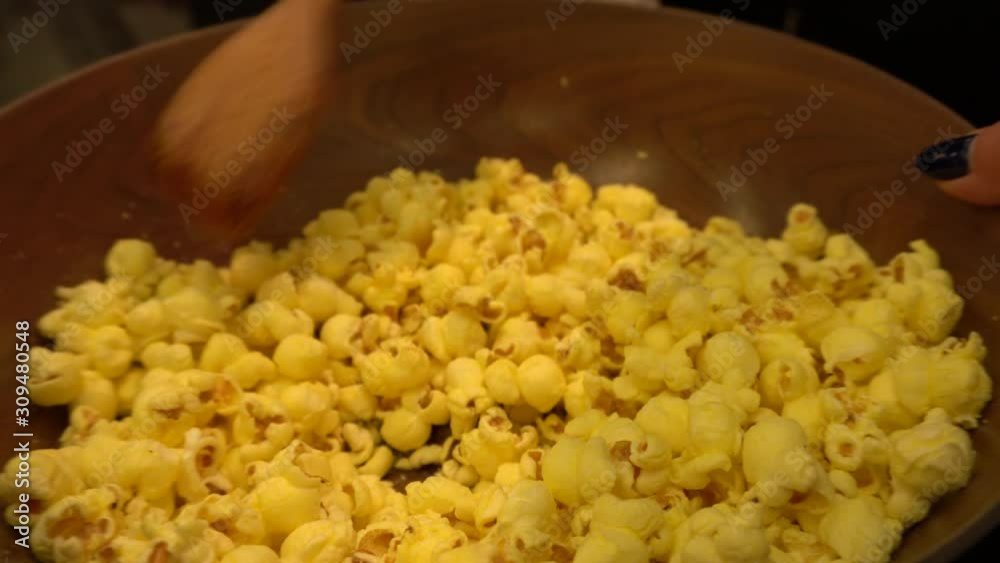 Vidéo Stock Someone is mixing popcorn in a bowl made with wood. You can ...