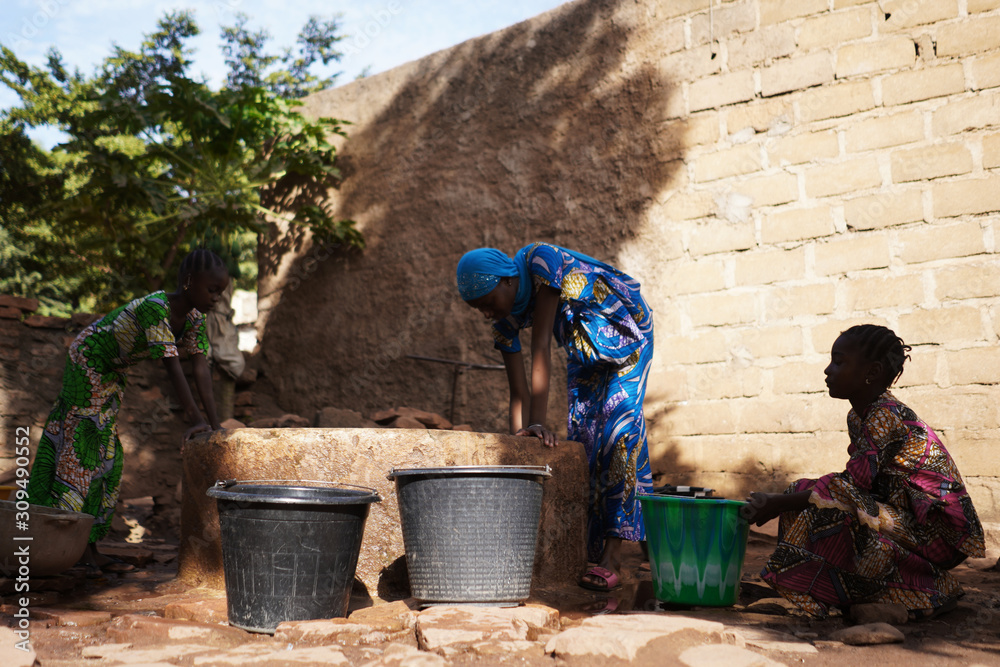 Black African Women Pouring Water into Bucket Stock Photo | Adobe Stock