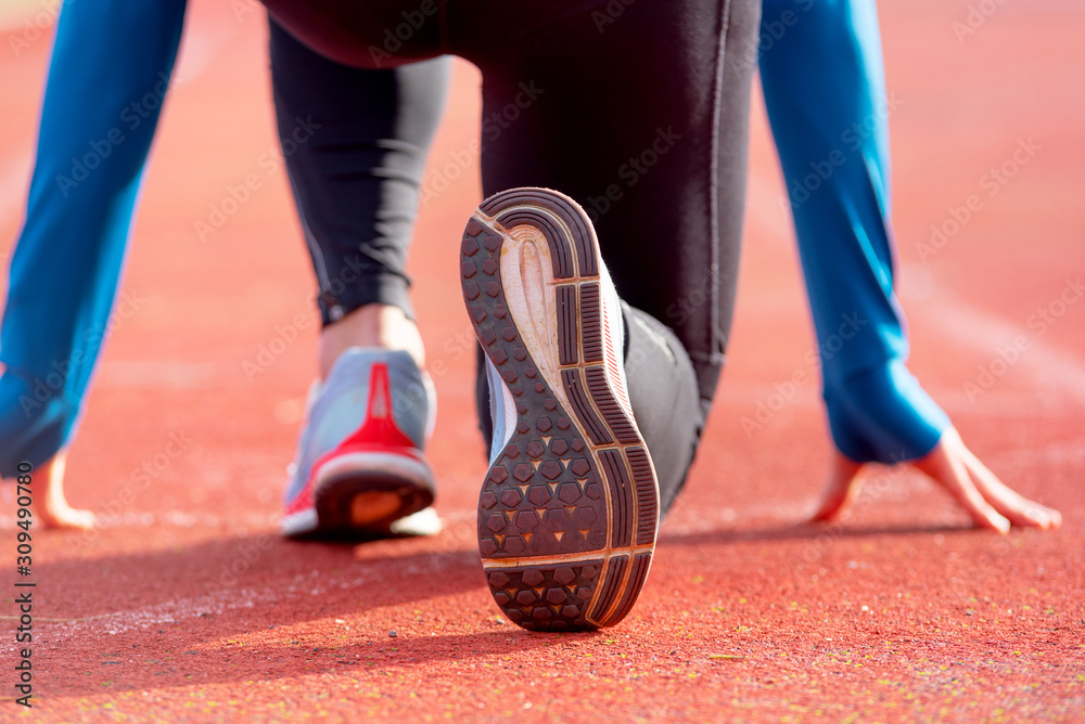 Back view of an athlete getting ready for the race on a running track ...