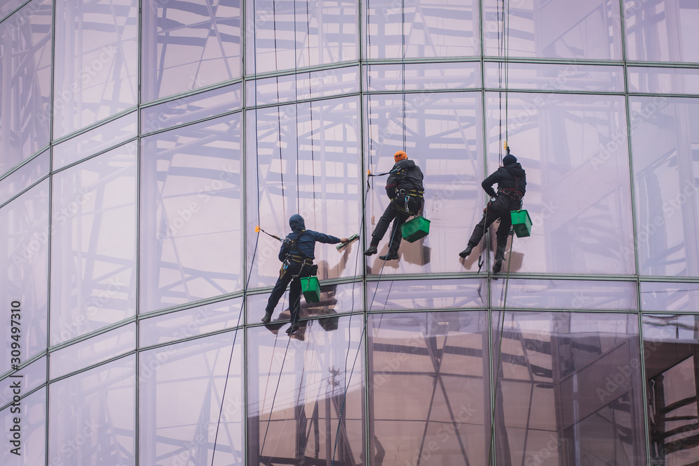 Group of workers cleaning the windows on the high rise building ...