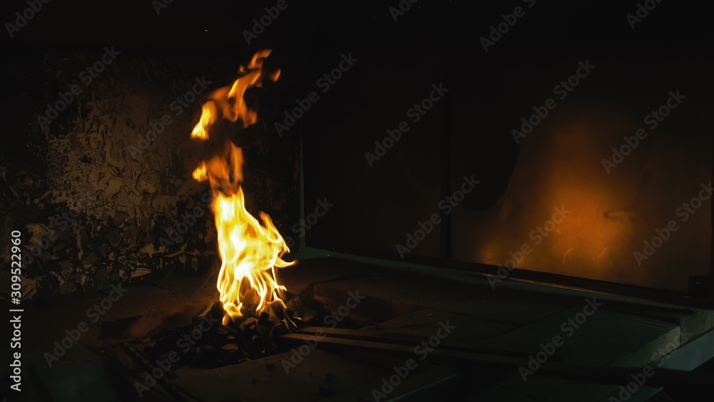 Forge fire in furnace. Blacksmith tempers a steel product in a stove ...