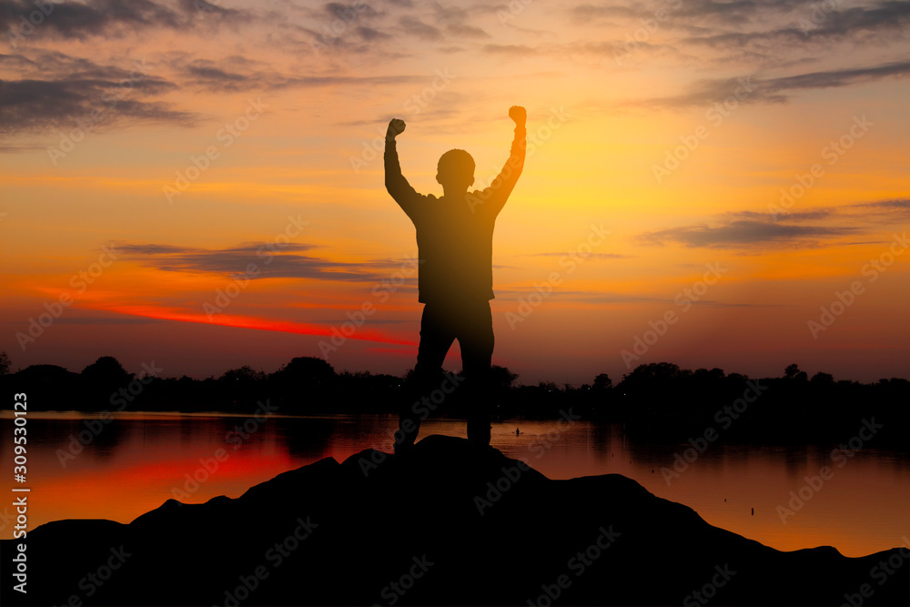 Silhouette of a happy man raised hands up as a successful, victory and ...