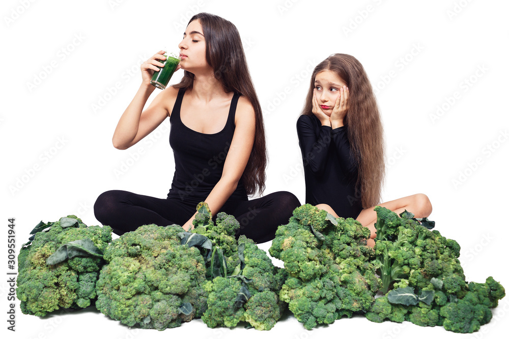 two girls are sitting in a big pile of broccoli. girl drinks green ...