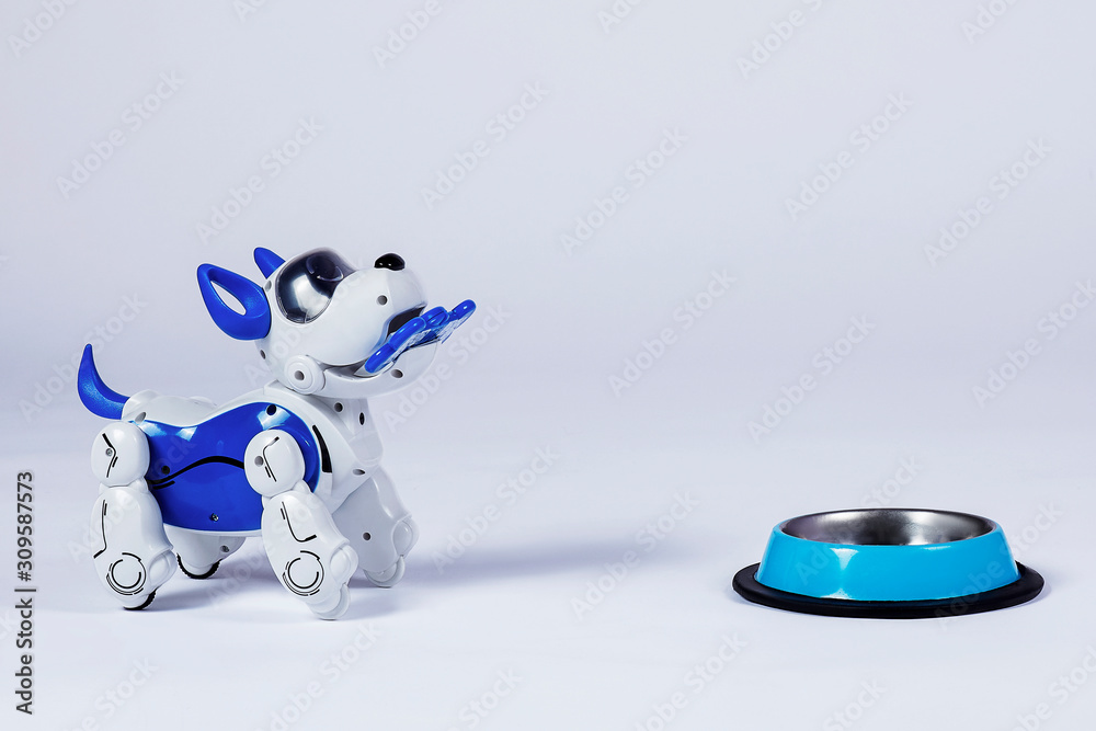 Electronic interactive toy dog puppy with a bone in mouth stands in ...