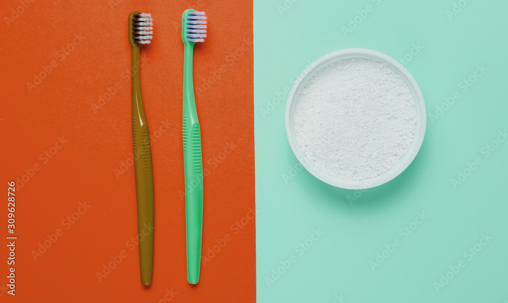 Two toothbrushes, tooth powder on orange blue background. Minimalism ...