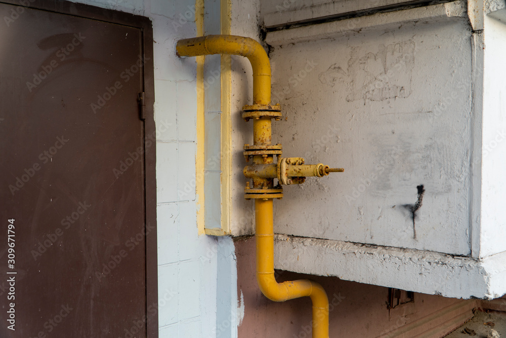 Old yellow gas valve on the pipe near balcony and brown steel door ...