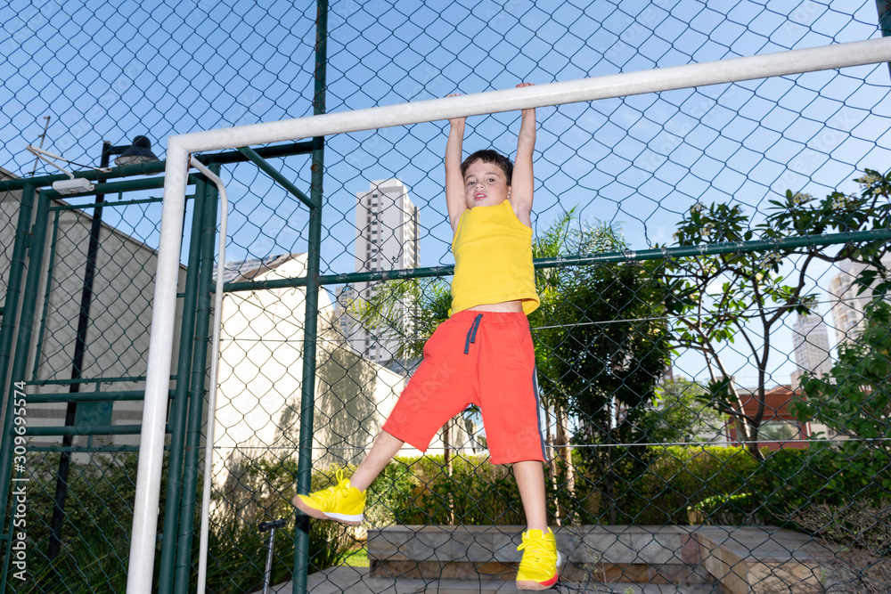 6 year old boy hanging on the soccer goalpost (photo 2). Stock Photo ...