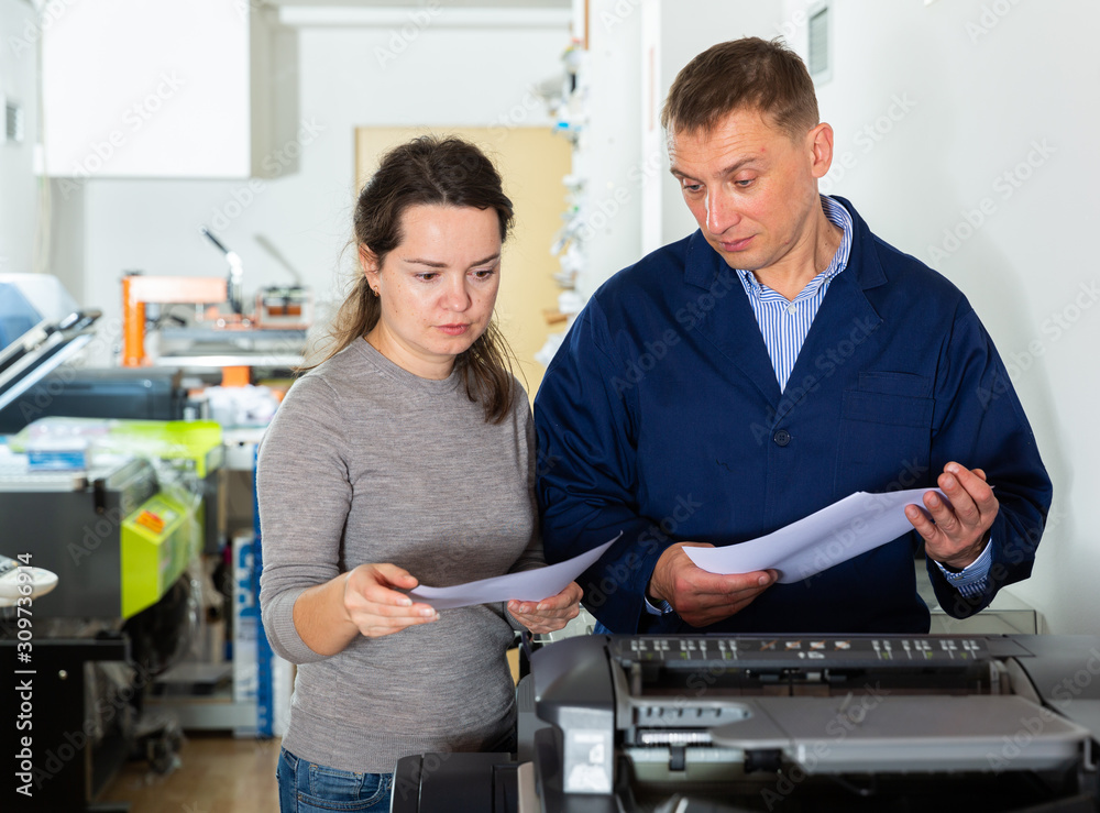 Female designer and print operator working together at the print ...