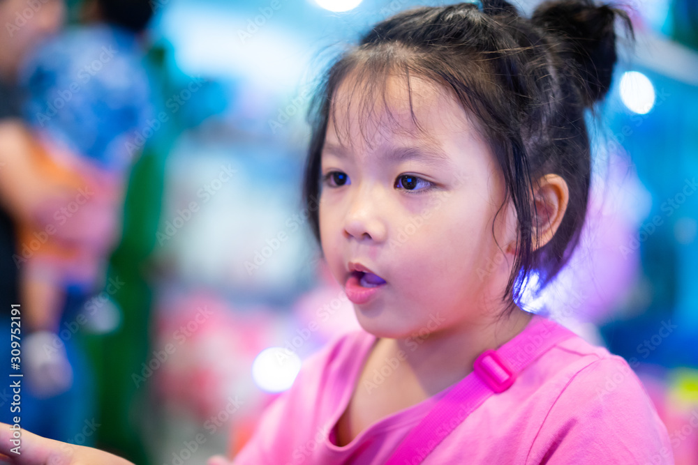 Little asian girl playing Racing car arcade game machine in Game center ...